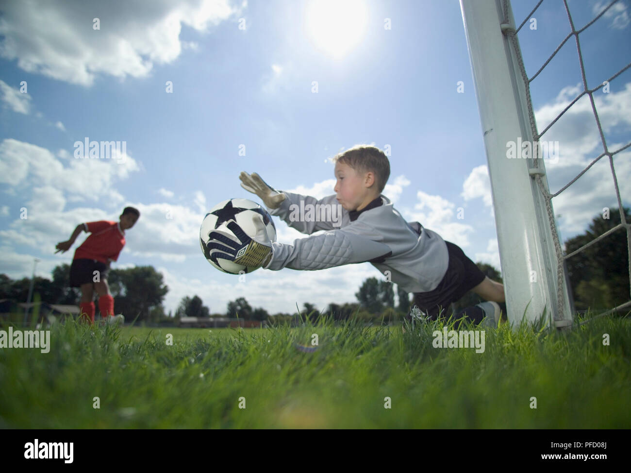 Boy in goal diving to save the ball from another boy Stock Photo - Alamy