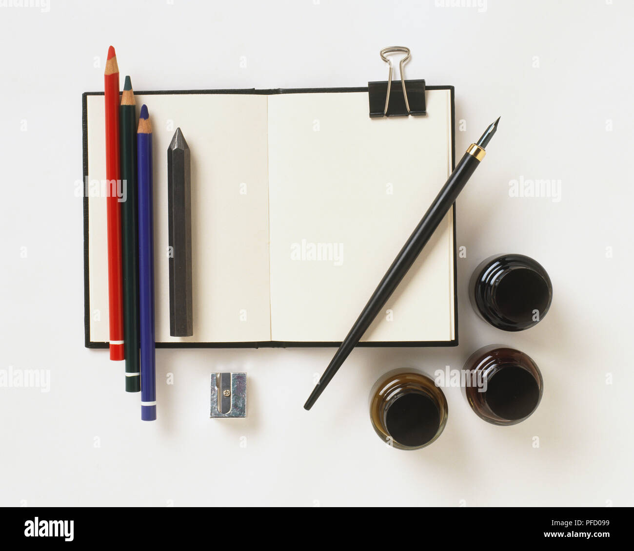 Sketch pad opened beside a range of inks, fountain pen and pencils ...