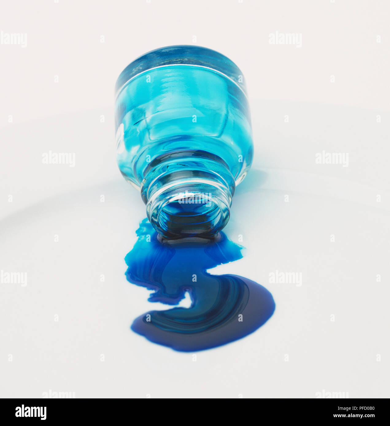 Blue ink pouring out of glass pot onto a white plate, front view Stock ...