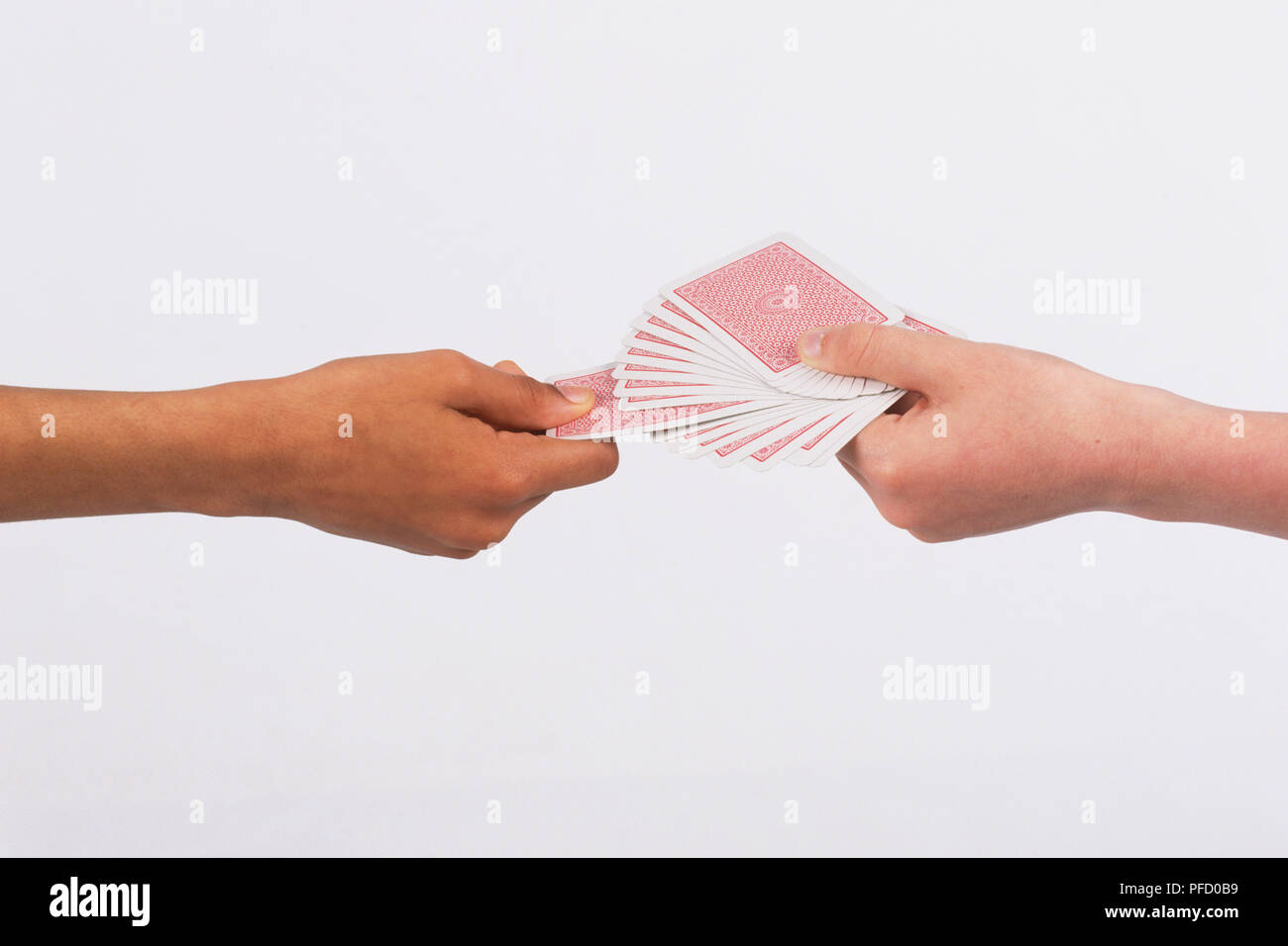 Hand pulling playing card out of down-facing deck held in another ...