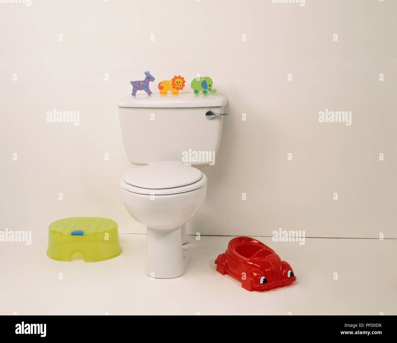 White toilet with toy zebra, lion and elephant placed on cistern ...