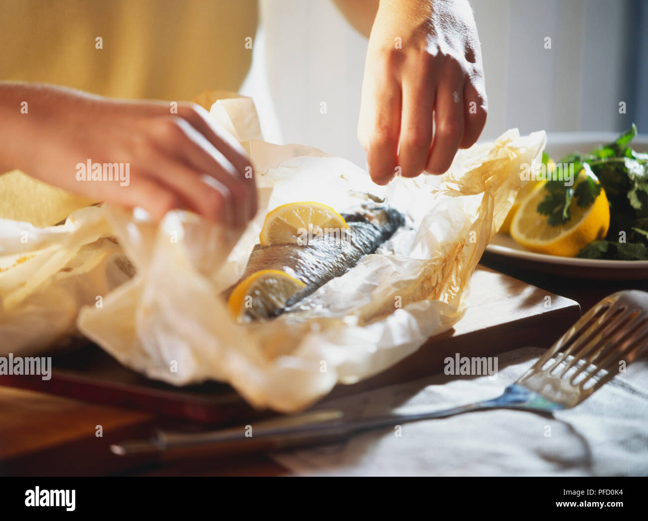 Whole fish decorated with lemon slices being unwrapped from paper ...