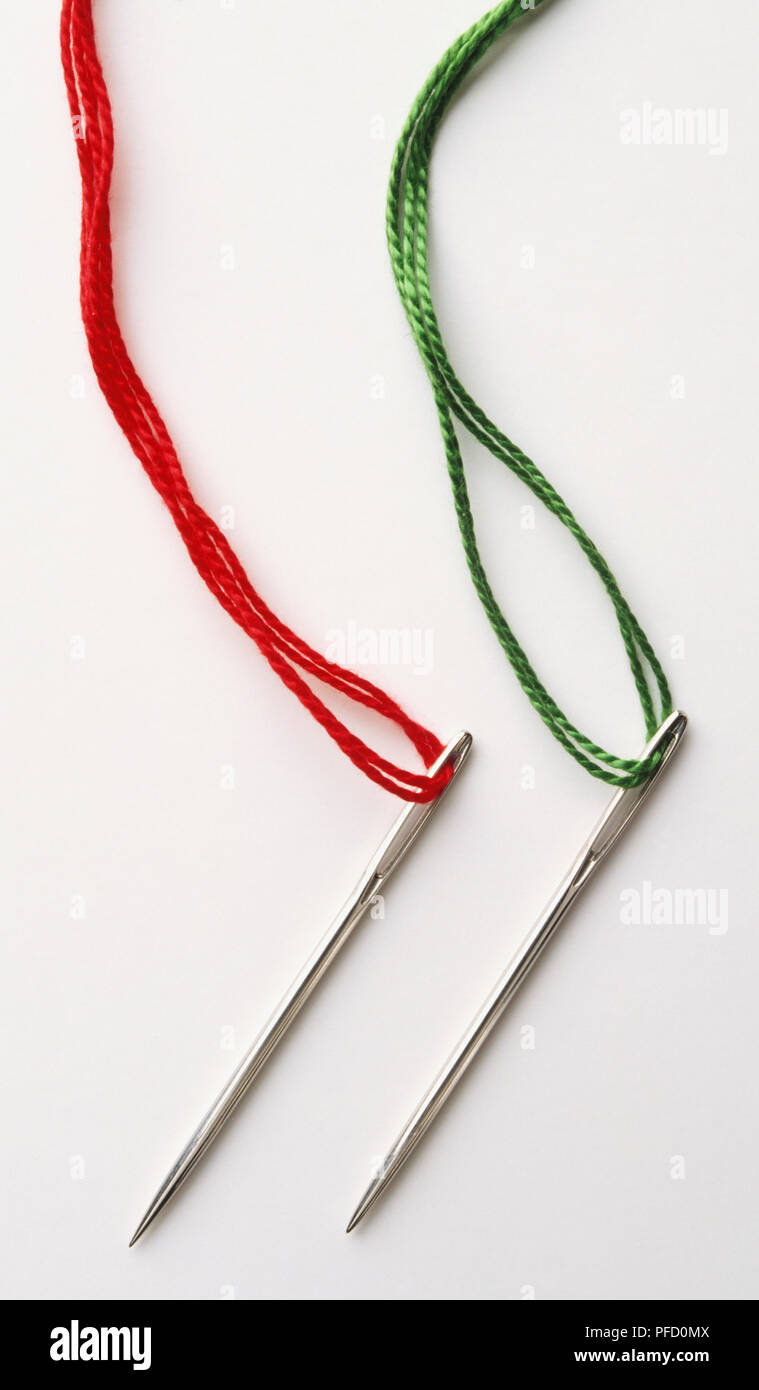 Two threaded sewing needles with green and red threads, close up Stock ...