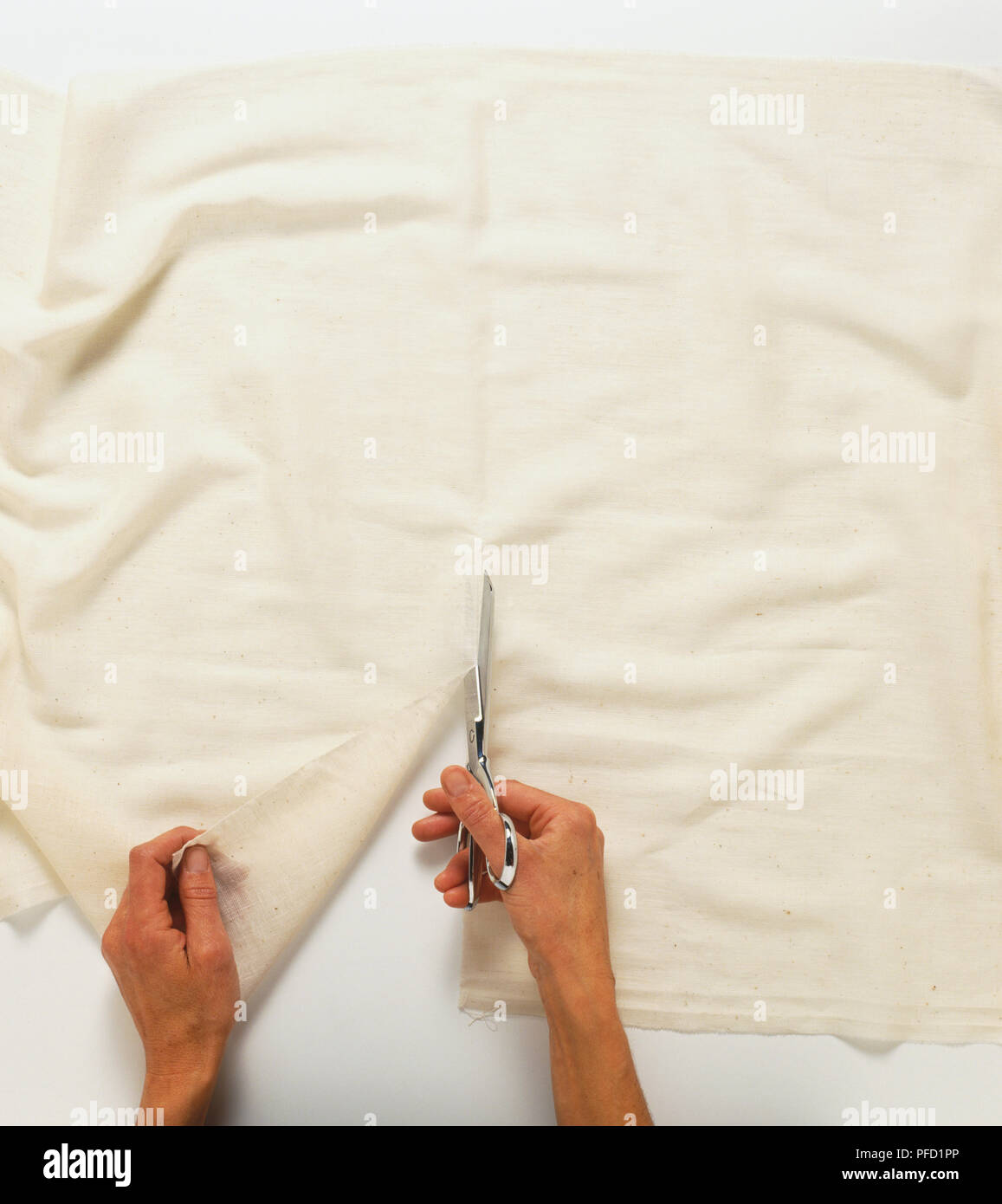 Cutting white curtain fabric using pair of dressmaker's scissors, view ...