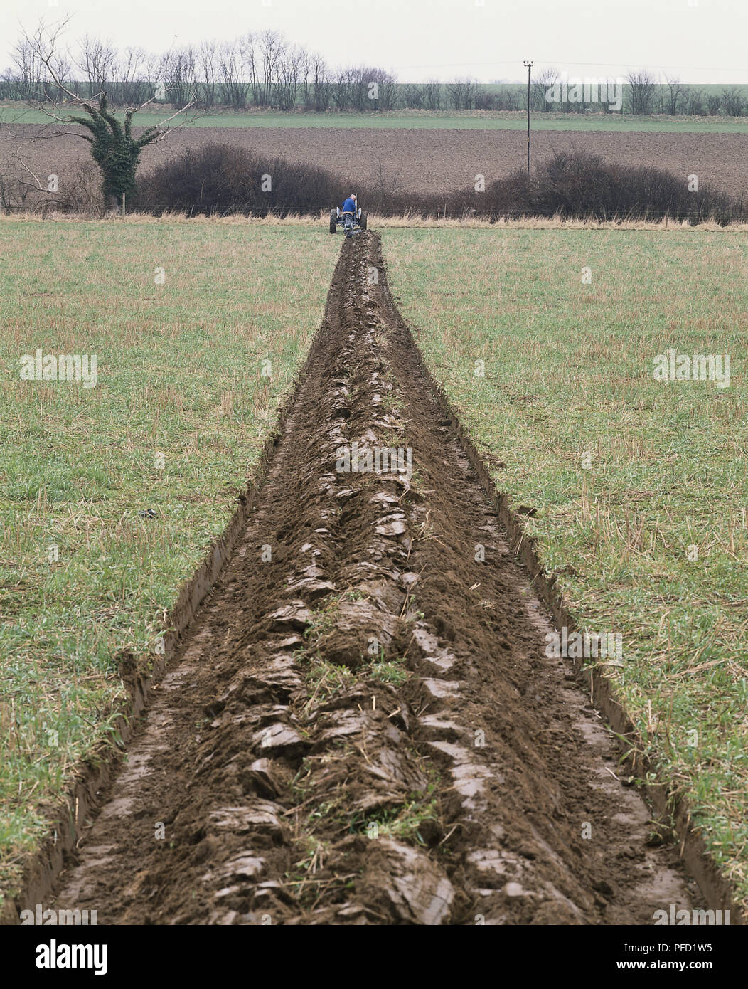 Farmer using tractor to plough furrows in field Stock Photo - Alamy