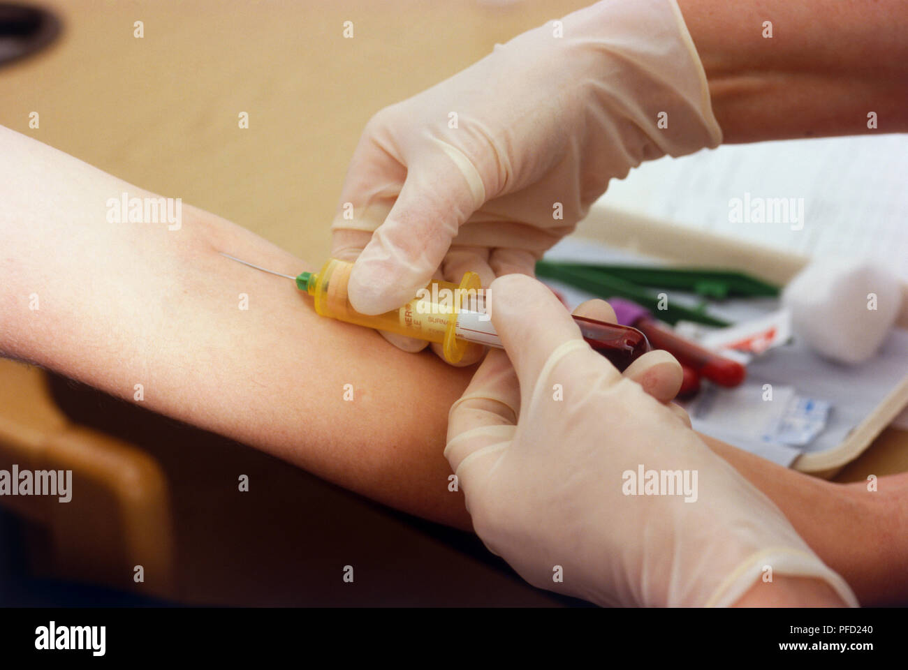 Person wearing surgical gloves using syringe to take blood sample from ...