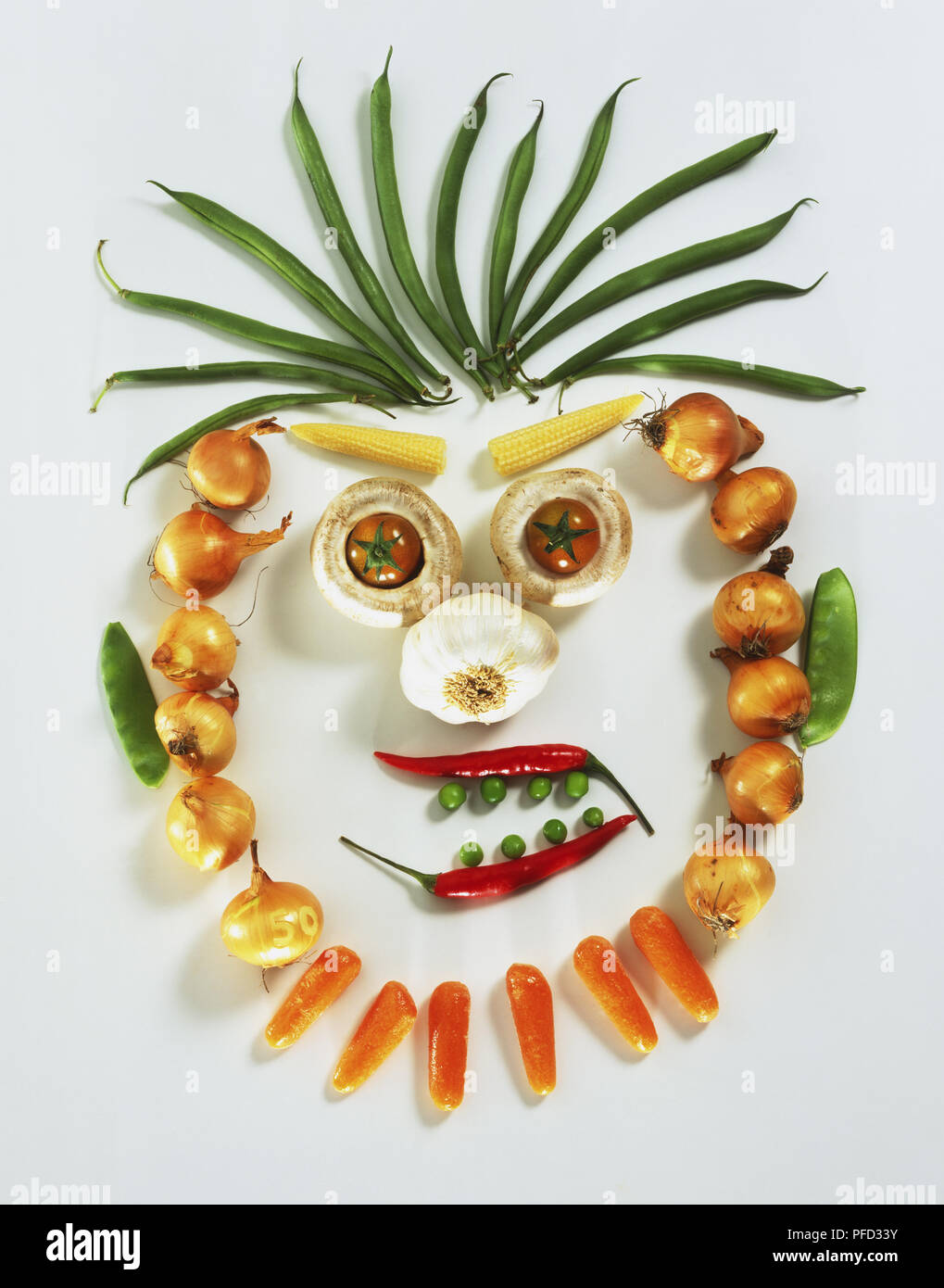 Selection of raw vegetables arranged in the shape of a face, view from ...