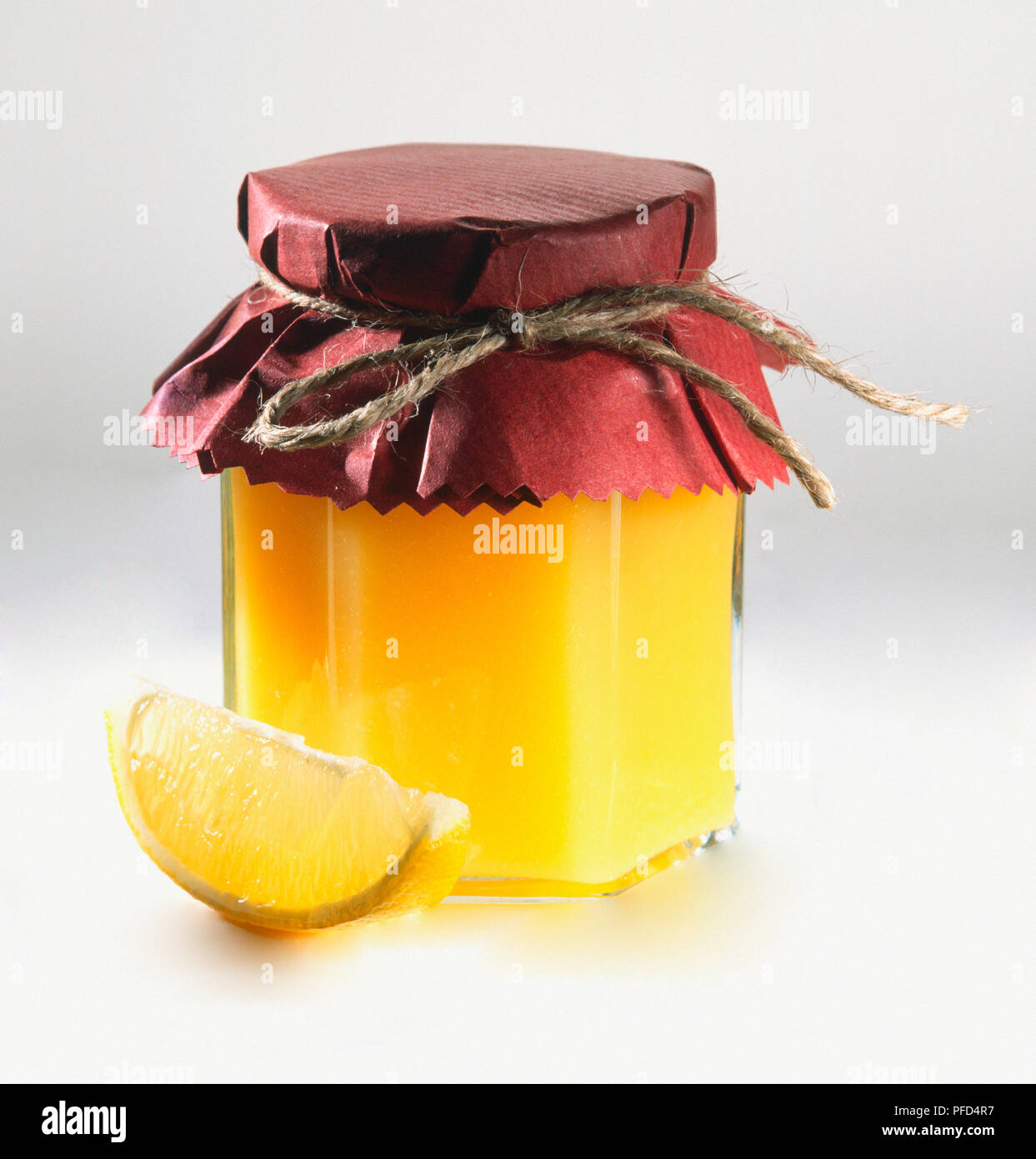 Lemon curd in glass jar with string tied around rim and slice of lemon ...