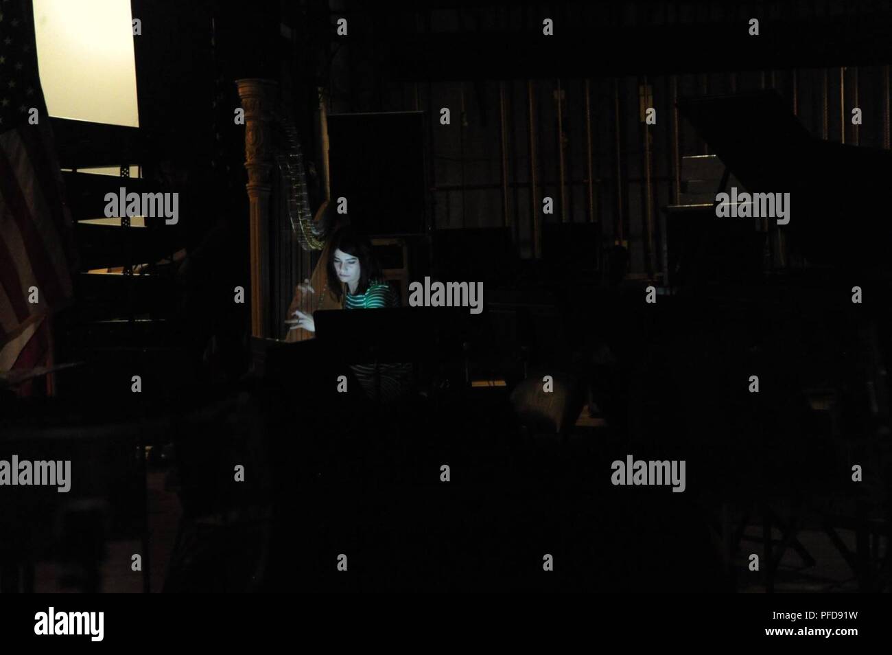 Coast Guard Chief Musician Megan Sesma warms up on the harp on a dark ...