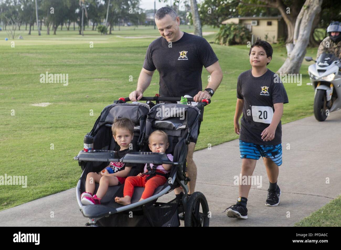 A race participant runs the Surf N’ Turf 5k with his children at the ...