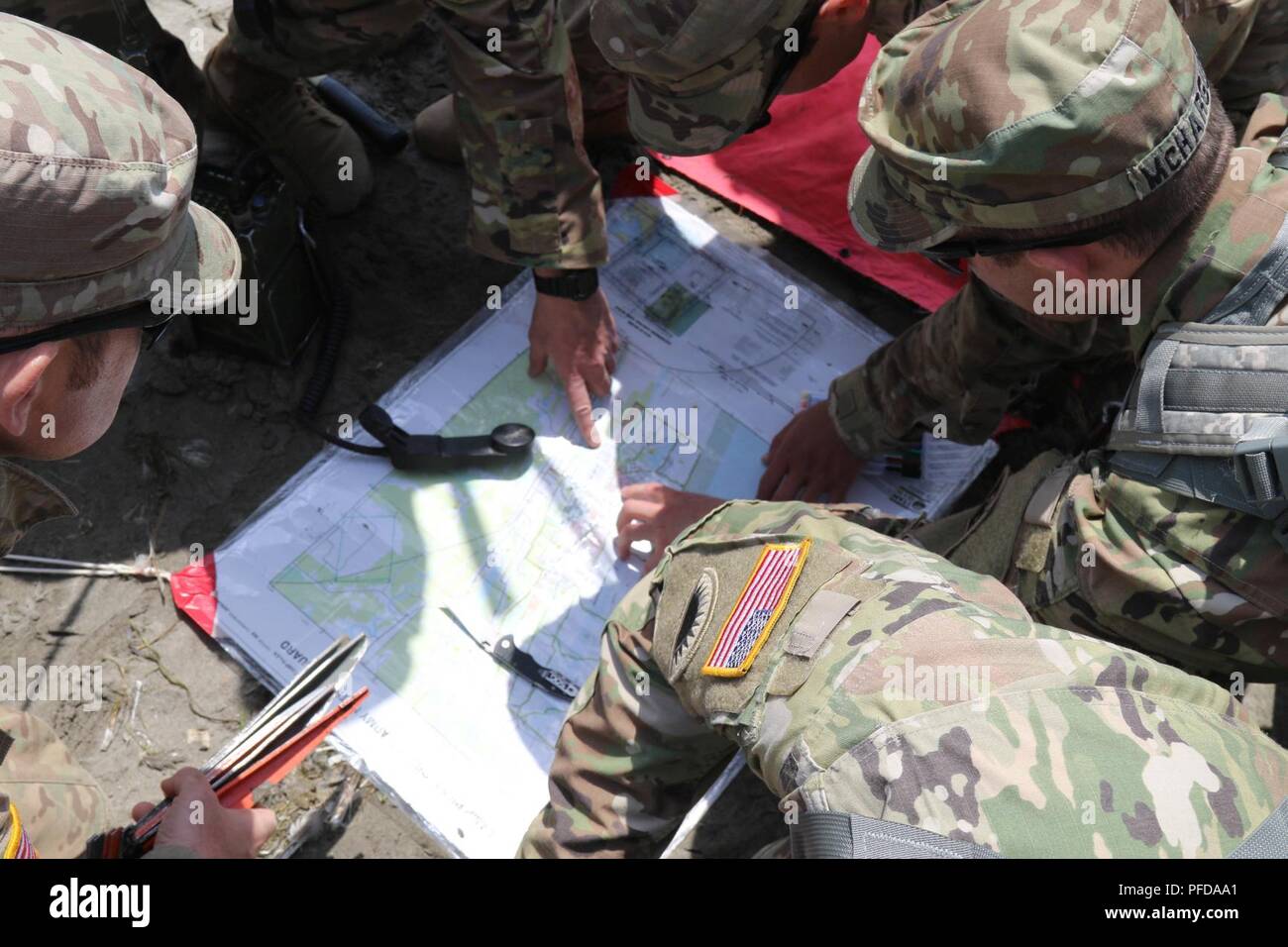 Soldiers check a map to decide the best drop zone for a box of ready-to ...