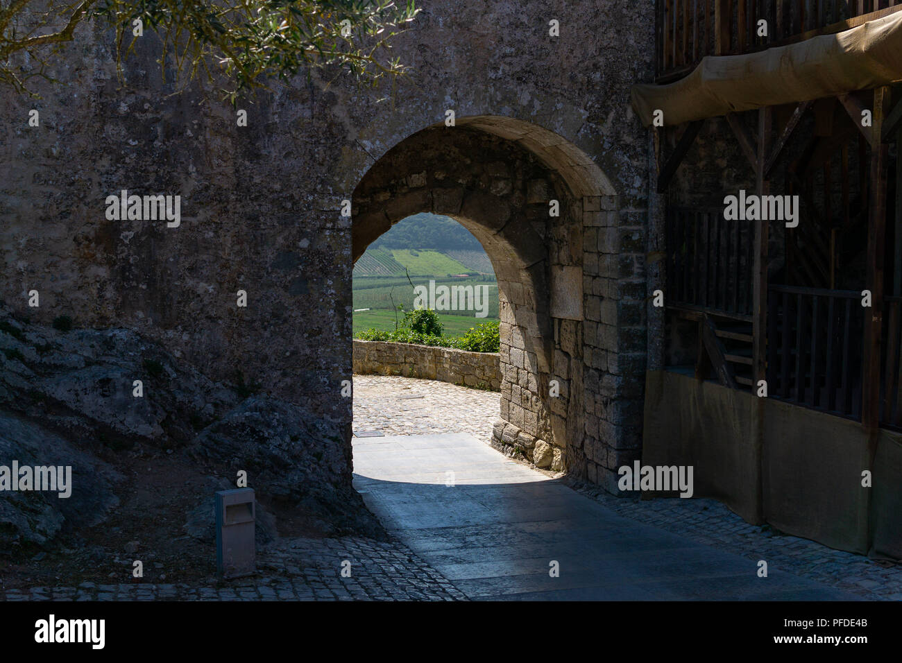 Looking through an archway in a castle wall to the green fields and ...