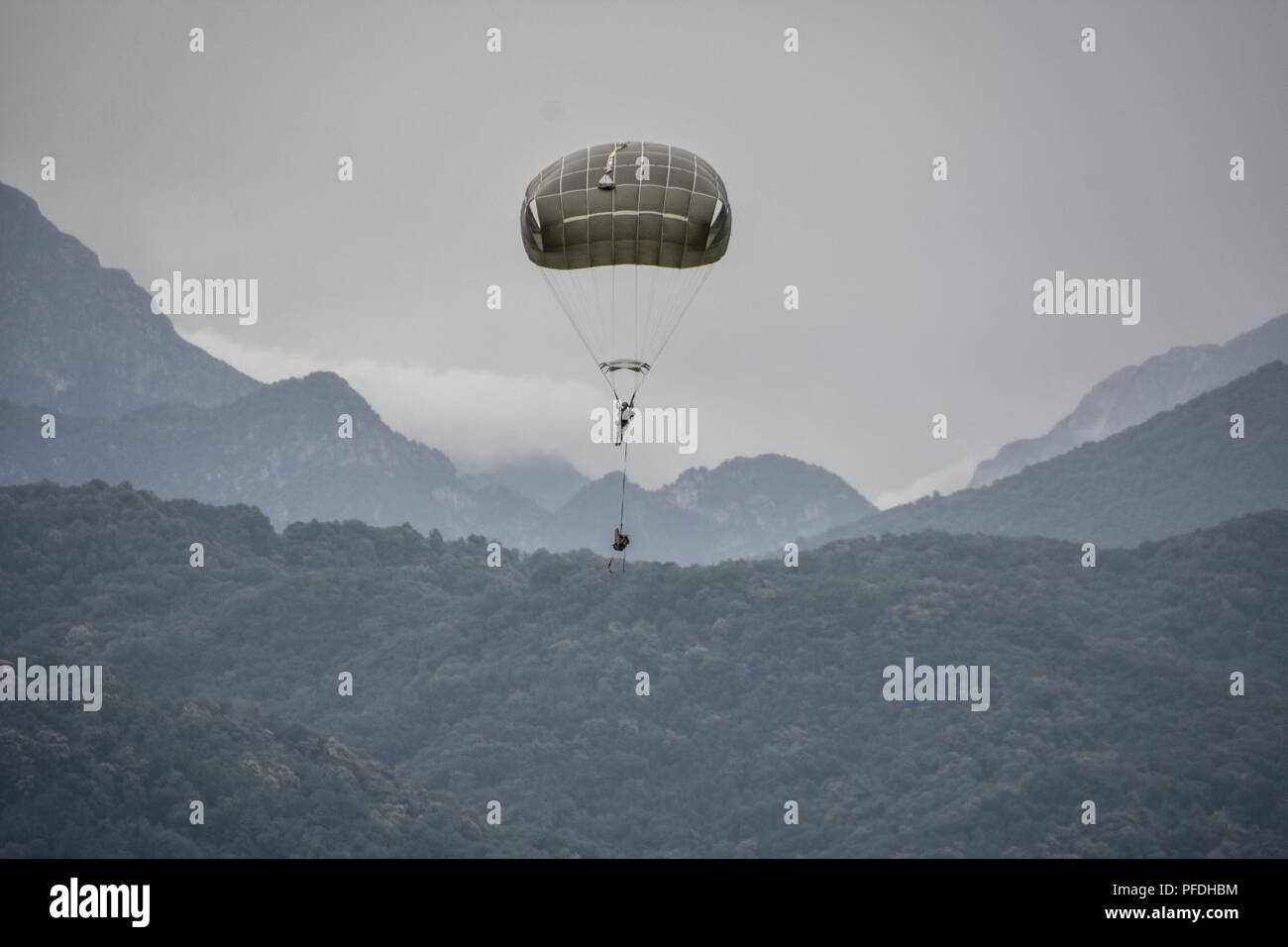A paratrooper descends past misty mountains as he joins 500 ...