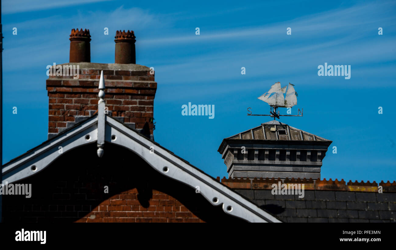 a weather vain with a sailing ship sits atpo roof tops in Ireland Stock ...