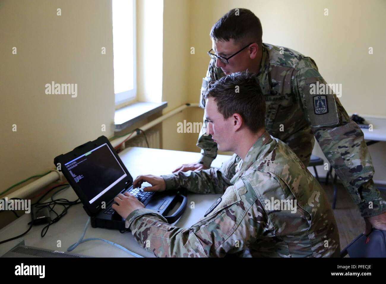 U.S. Army Spc. Erik Lundquist (at keyboard) and Sgt. Michael Cole, both ...