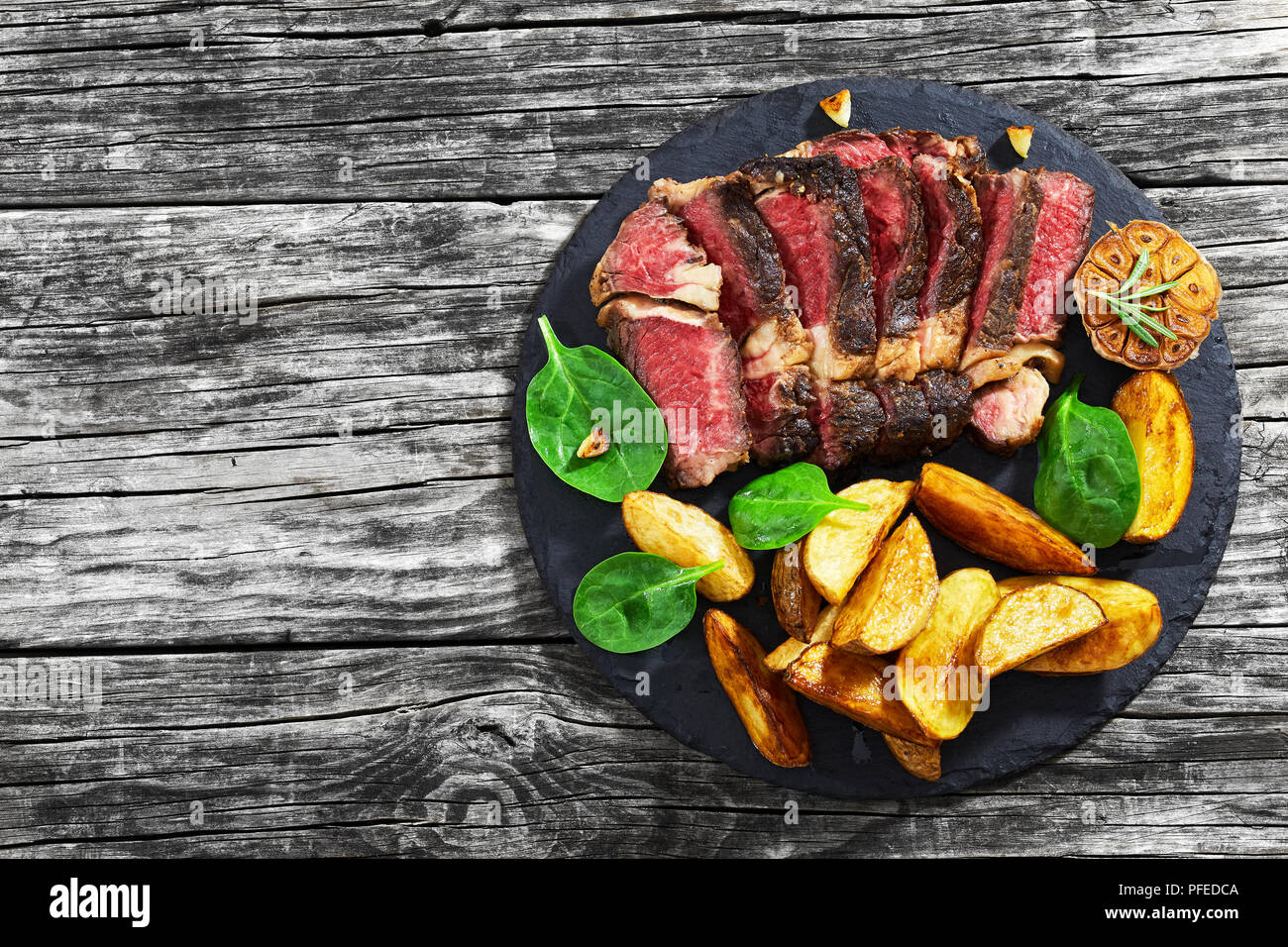 Juicy rib eye beef steak medium rare with spices cut in slices on slate ...
