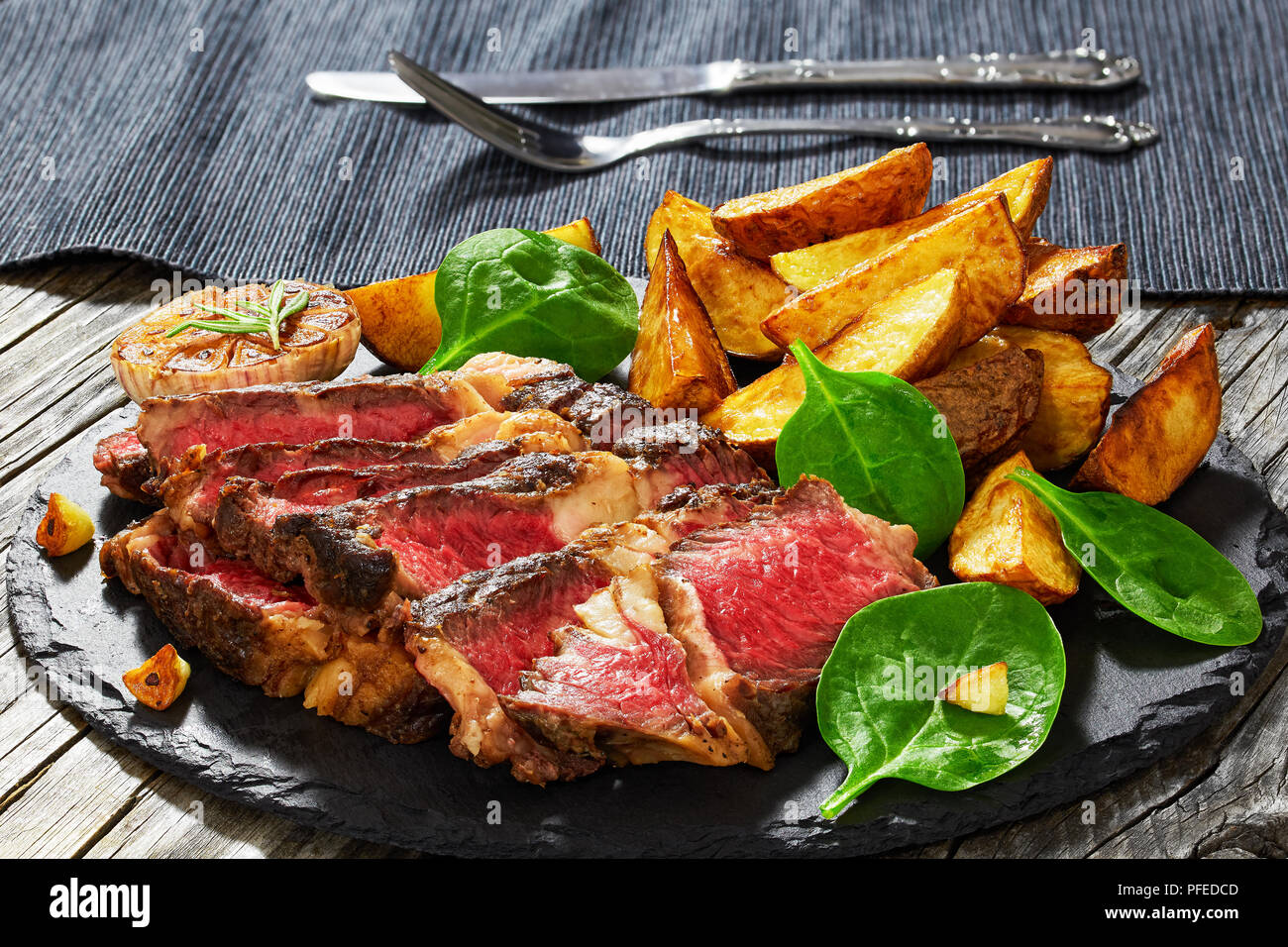Juicy rib eye beef steak medium rare with spices cut in slices on slate ...