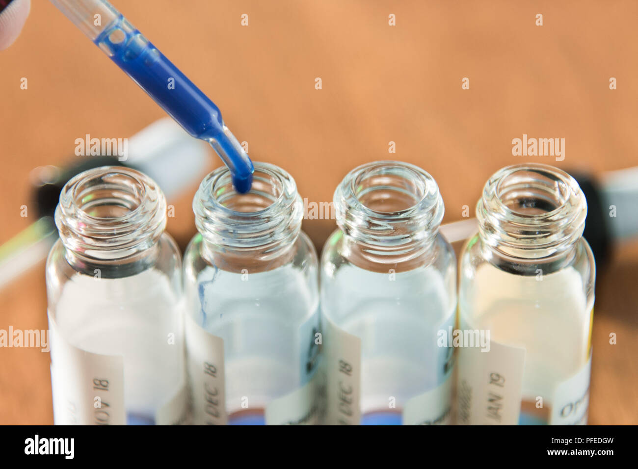 Laboratory glass items adding drop to one of several test tubes. A ...