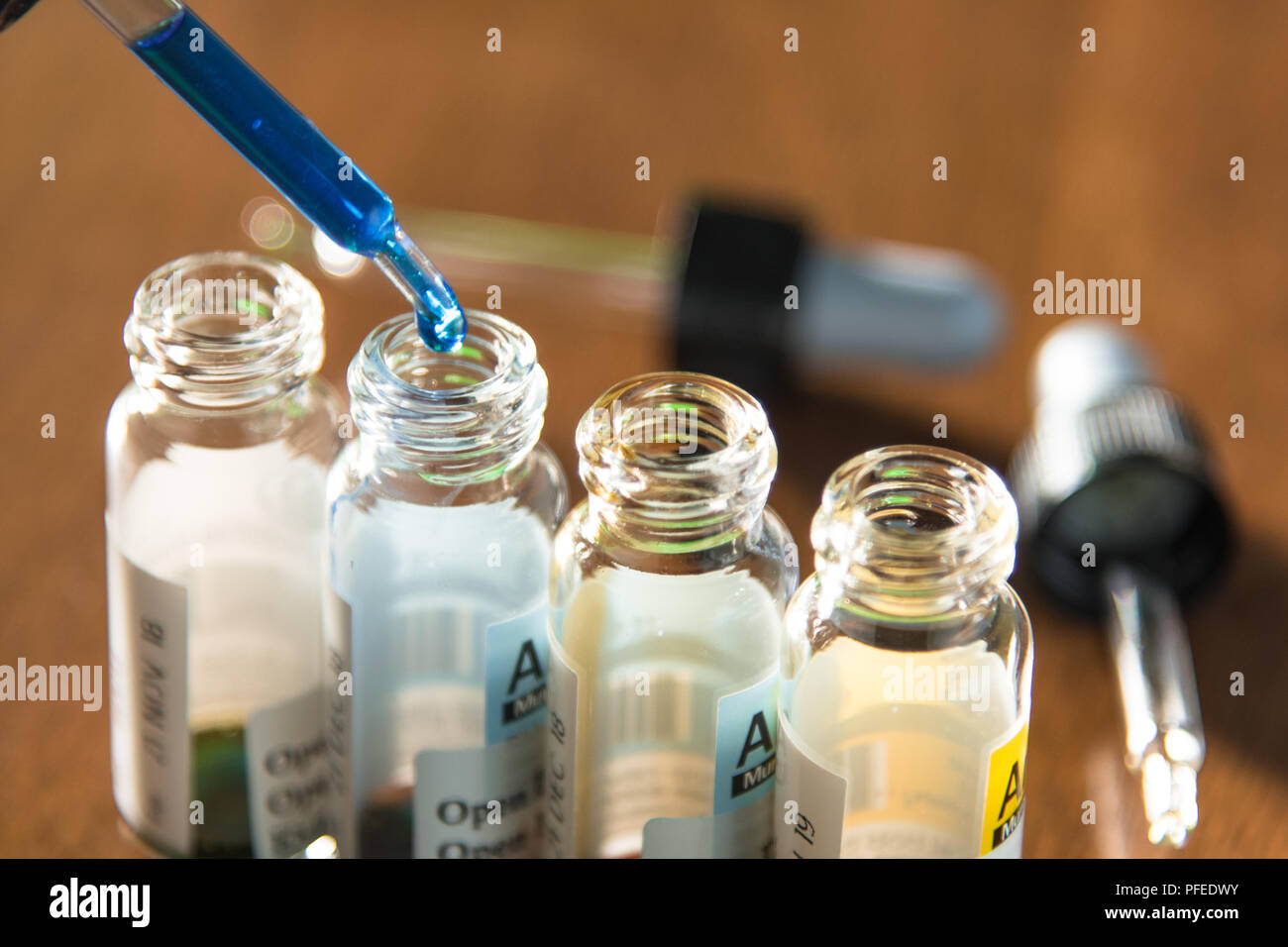 Laboratory glass items adding drop to one of several test tubes. A ...