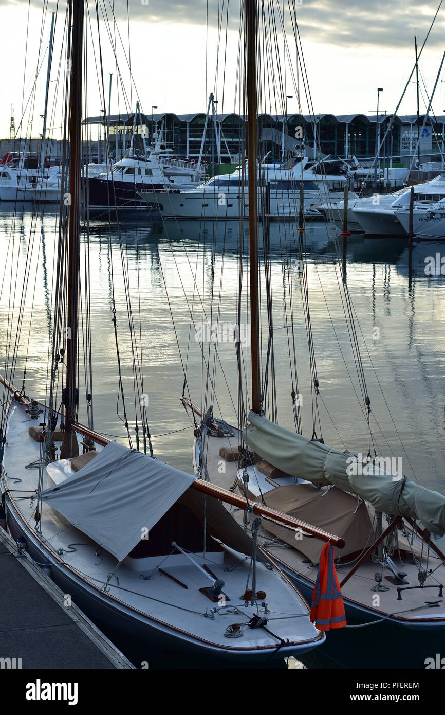 Two vintage sail boats tied to jetty in marina in evening with large ...