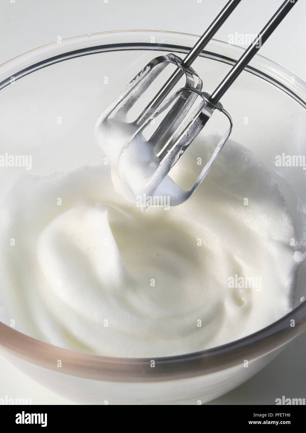 Electric mixer whisks lifted from whisked egg whites mixture, close up ...