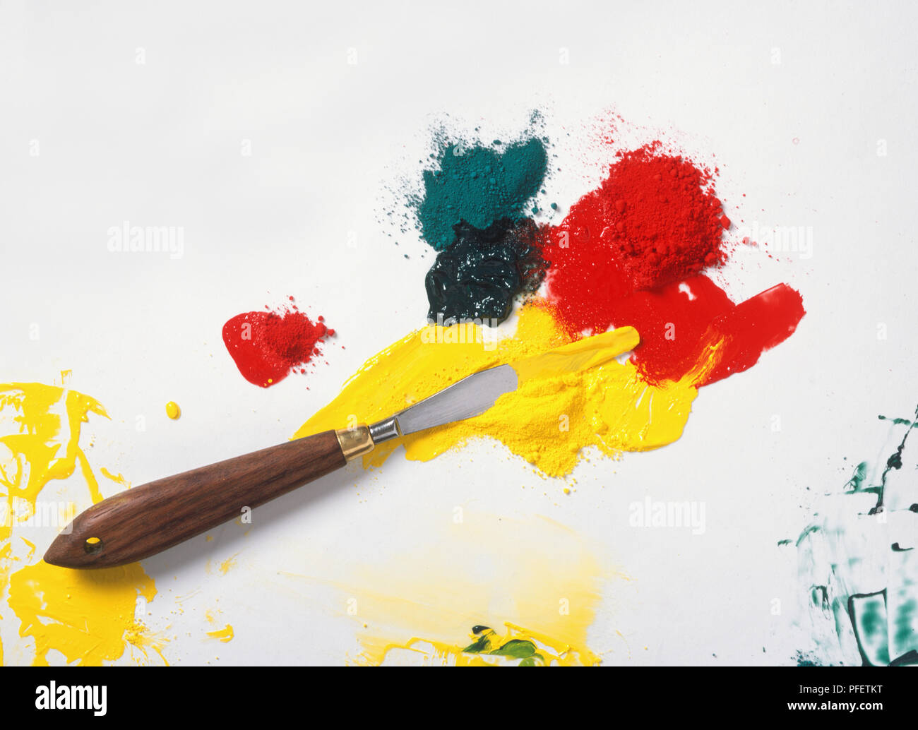 Three pigments, red, green, yellow being mixed with a palette knife ...
