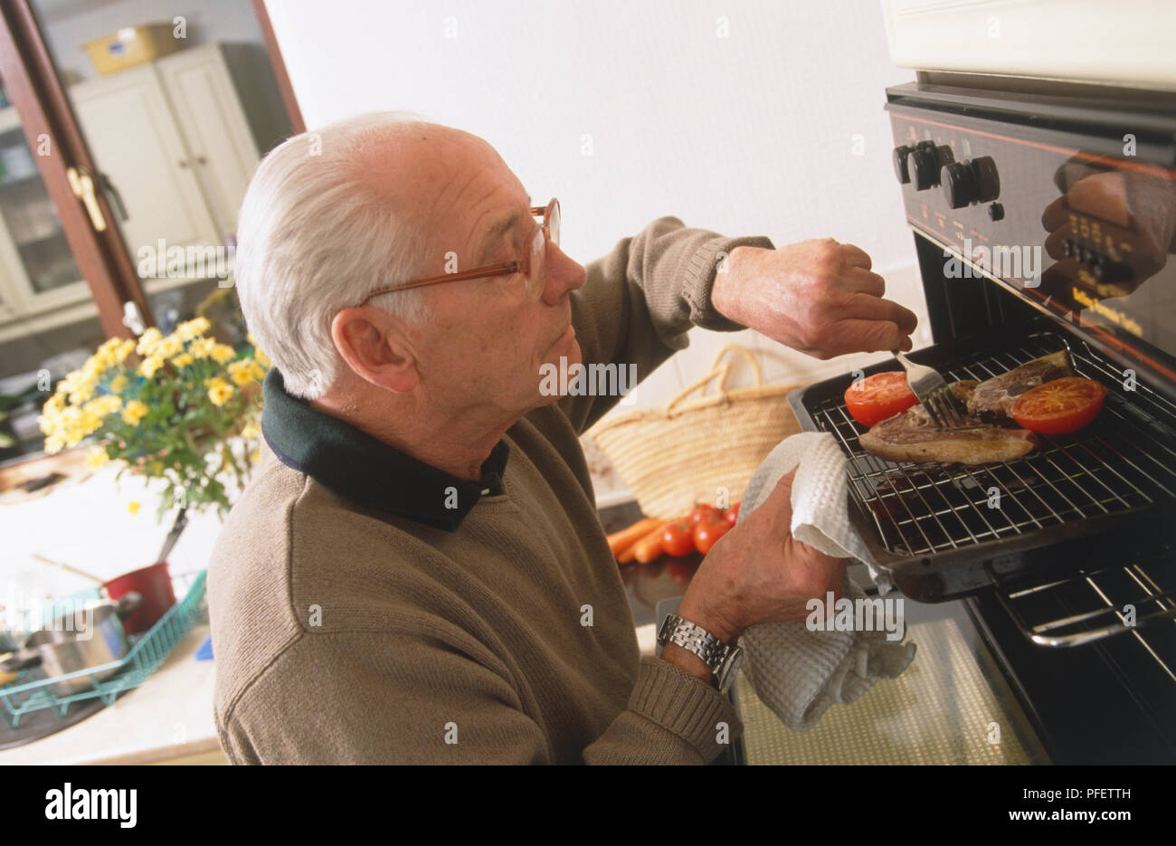 Elderly man cooking pork chop and tomato on a grill Stock Photo - Alamy