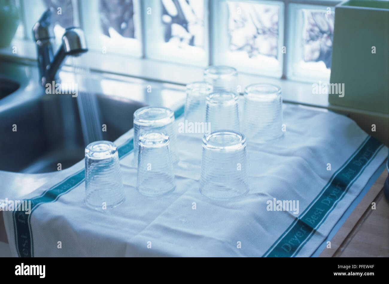 Drinking glasses drying upside down on cloth, next to kitchen sink ...