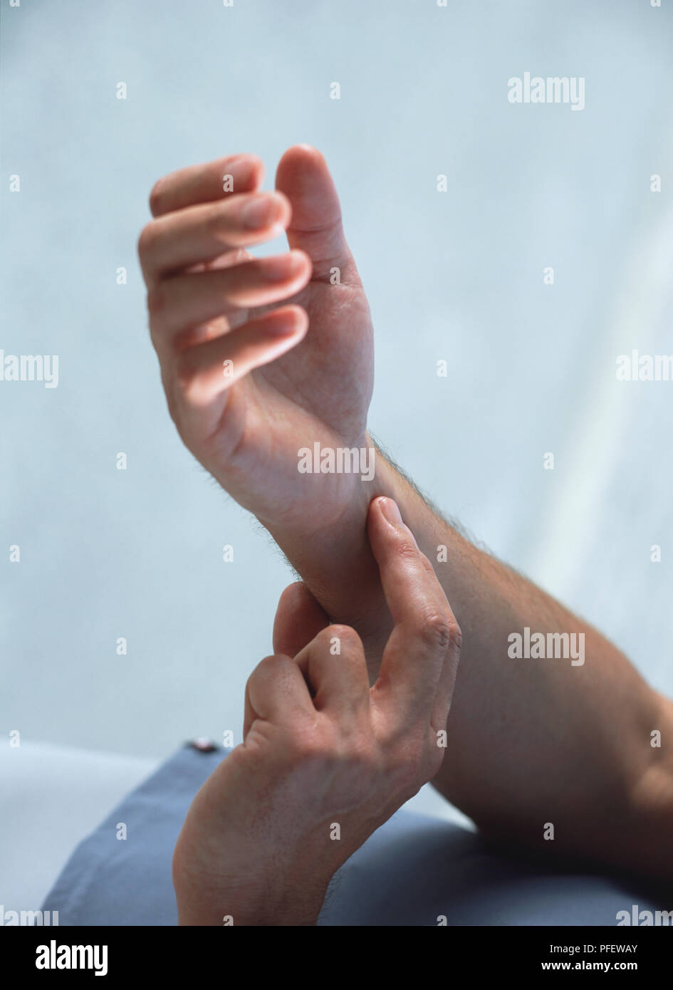 Man's forearm with palm upturned, thumb and two fingers of other hand ...