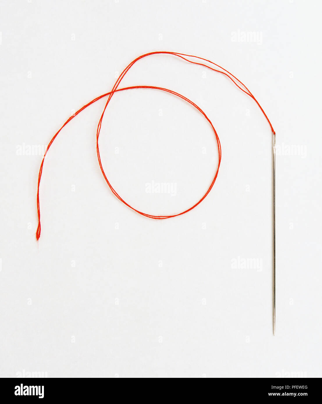 Sewing needle threaded with red thread Stock Photo - Alamy