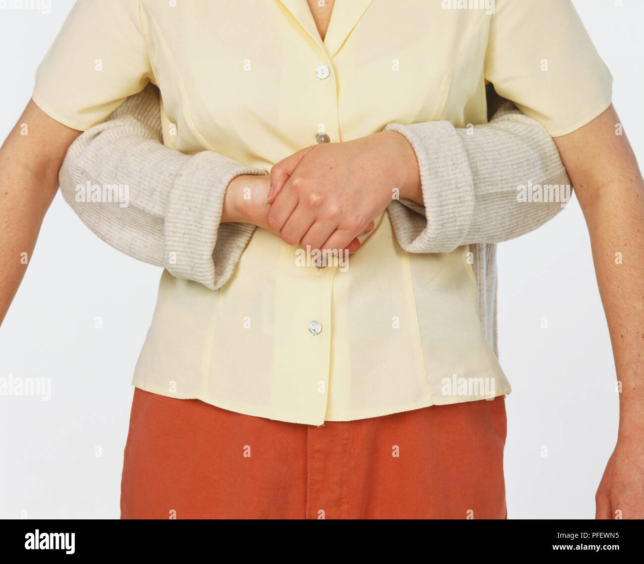 Torso of standing woman with another person's arms wrapped around her ...