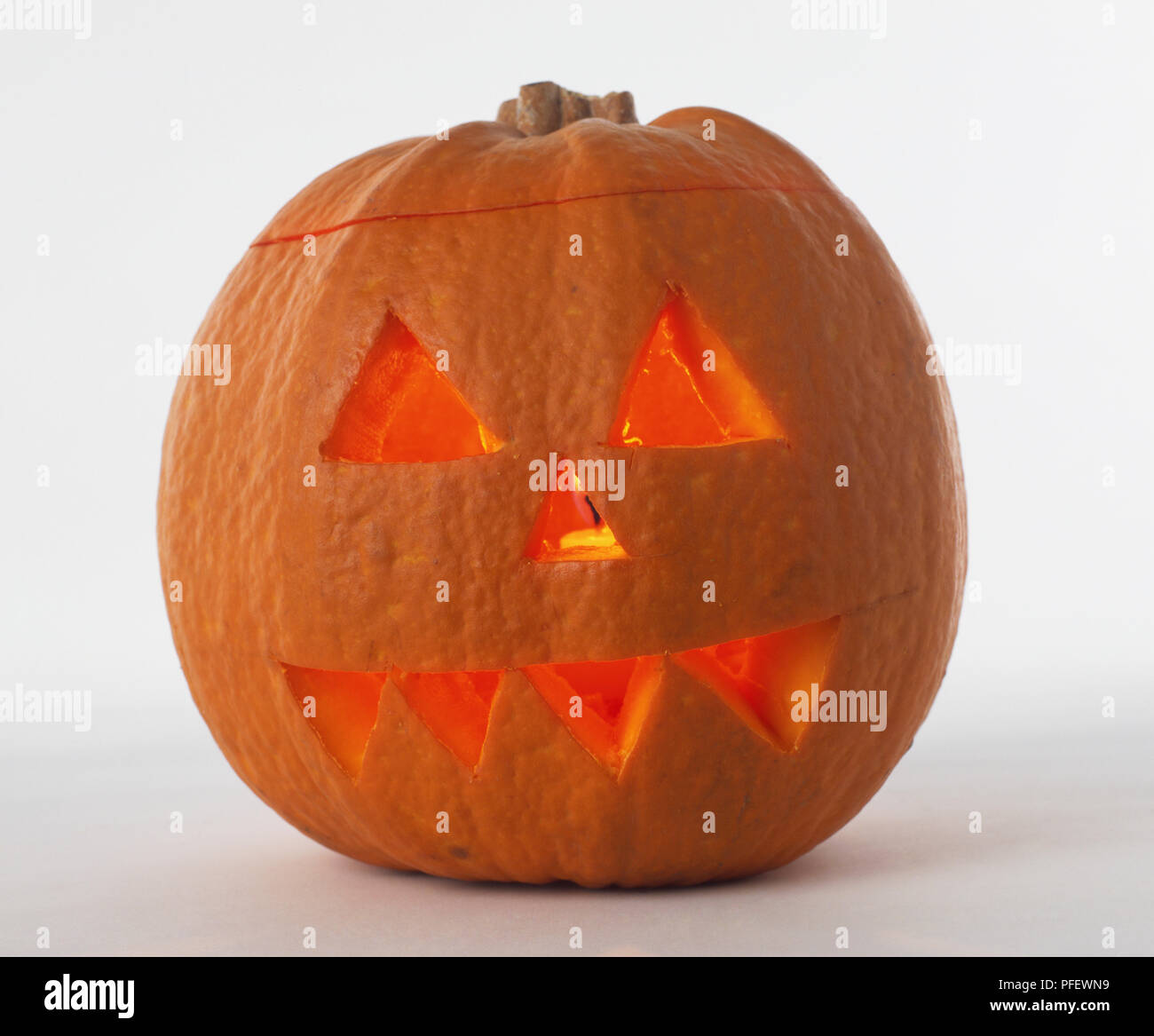 Pumpkin with triangular holes for eyes, nose and mouth and a candle lit ...