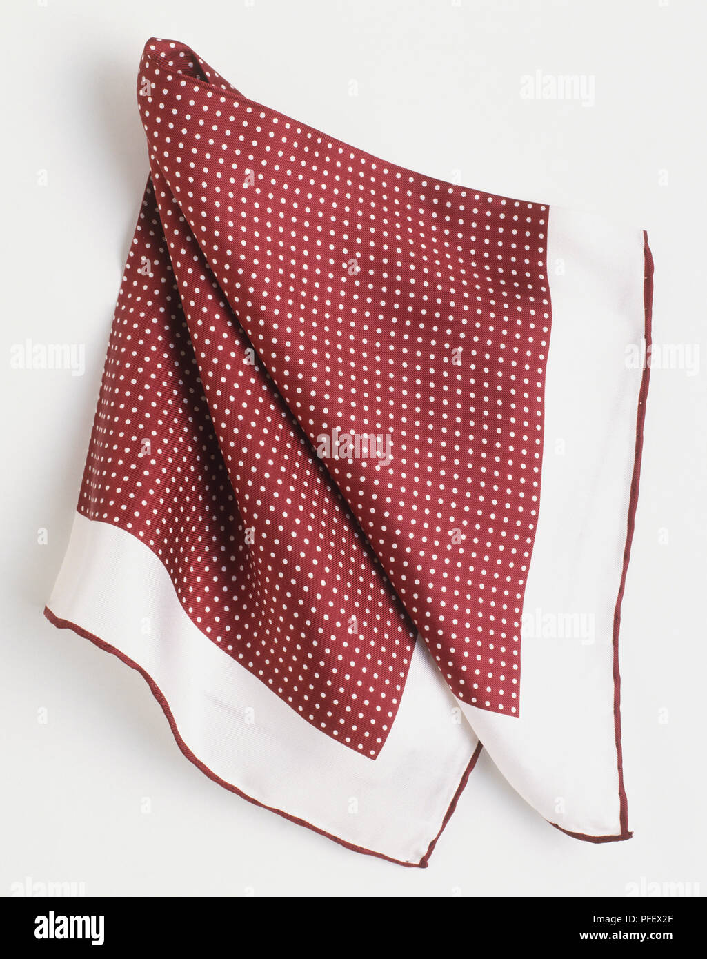 Folded red handkerchief with white border and polka dot pattern, close ...