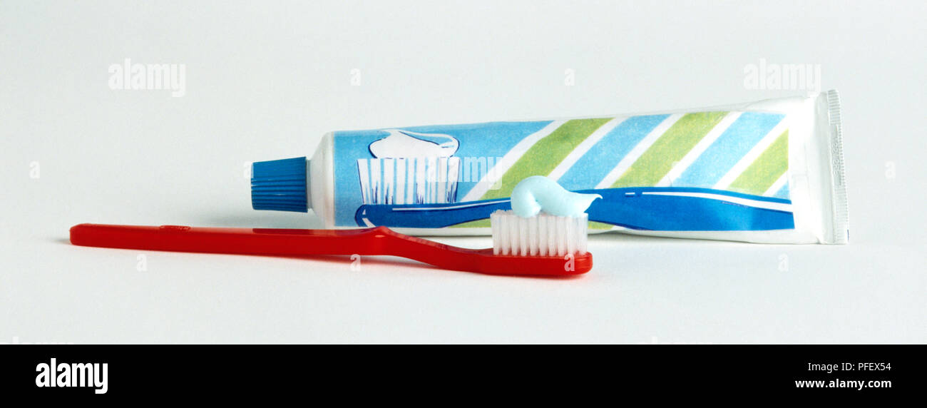 Tube of toothpaste and red toothbrush, side view Stock Photo - Alamy