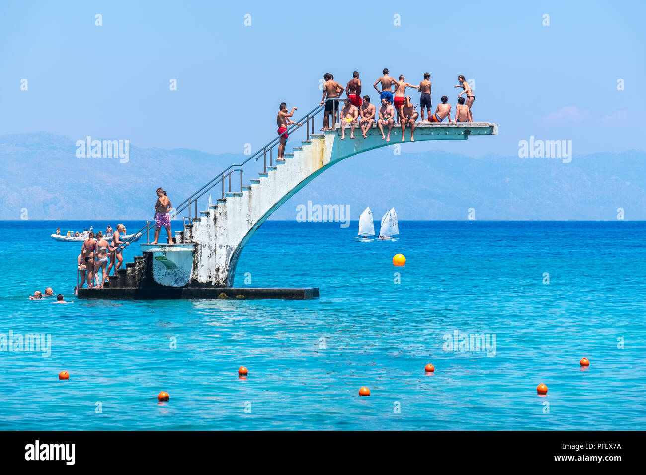 Many people having fun on diving board at Elli Beach, the main beach of ...