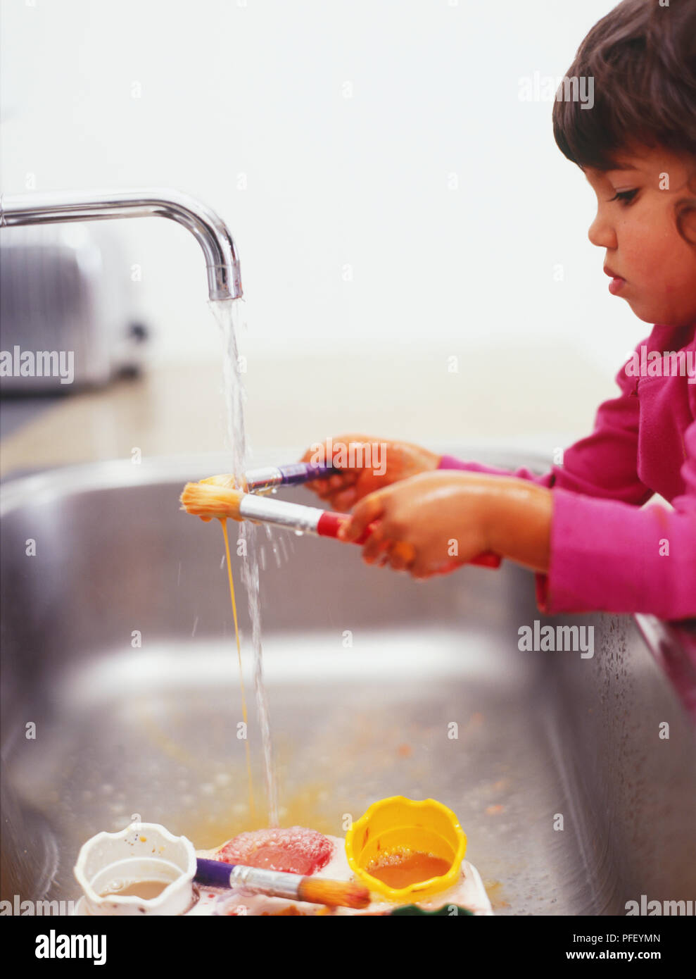 Girl cleaning paint brushes under running tap Stock Photo - Alamy