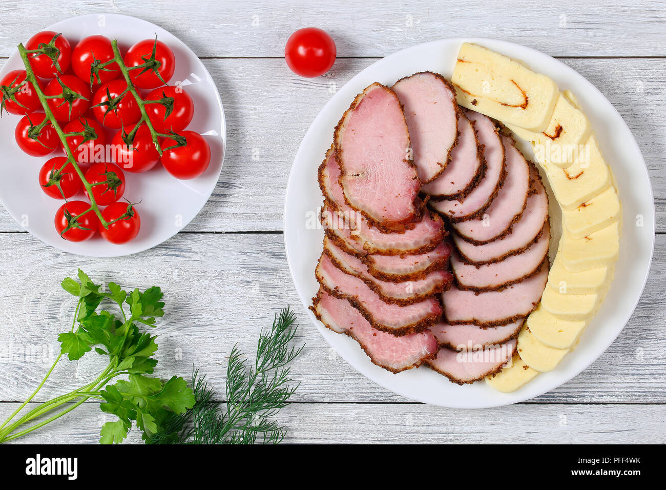 sliced cold meat and spicy mozzarella cheese on platter on white wooden ...