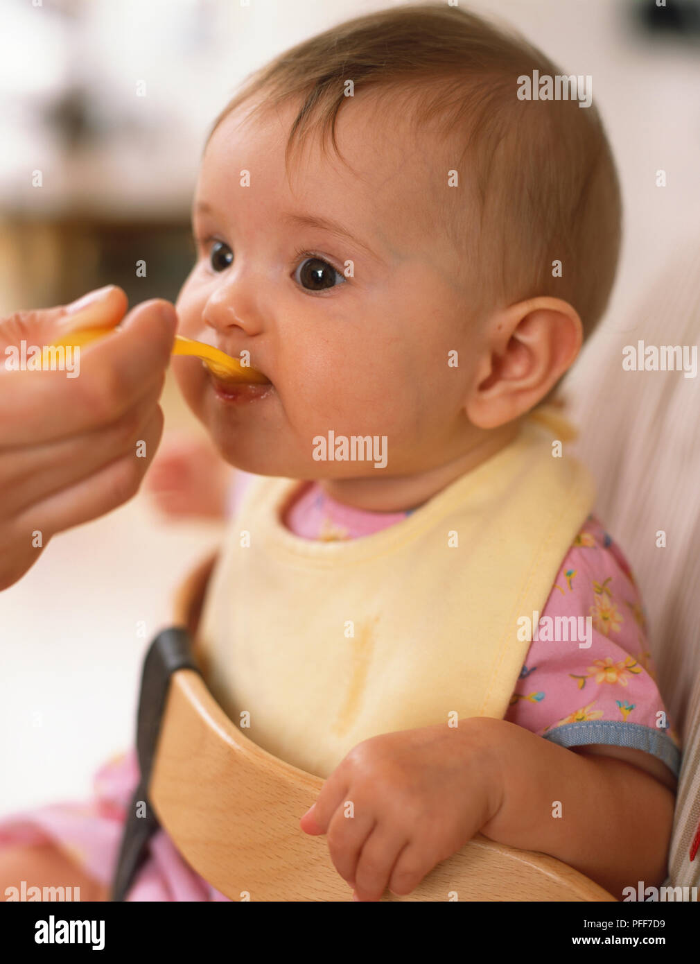Feeding a baby, sitting on highchair, with a spoon Stock Photo - Alamy