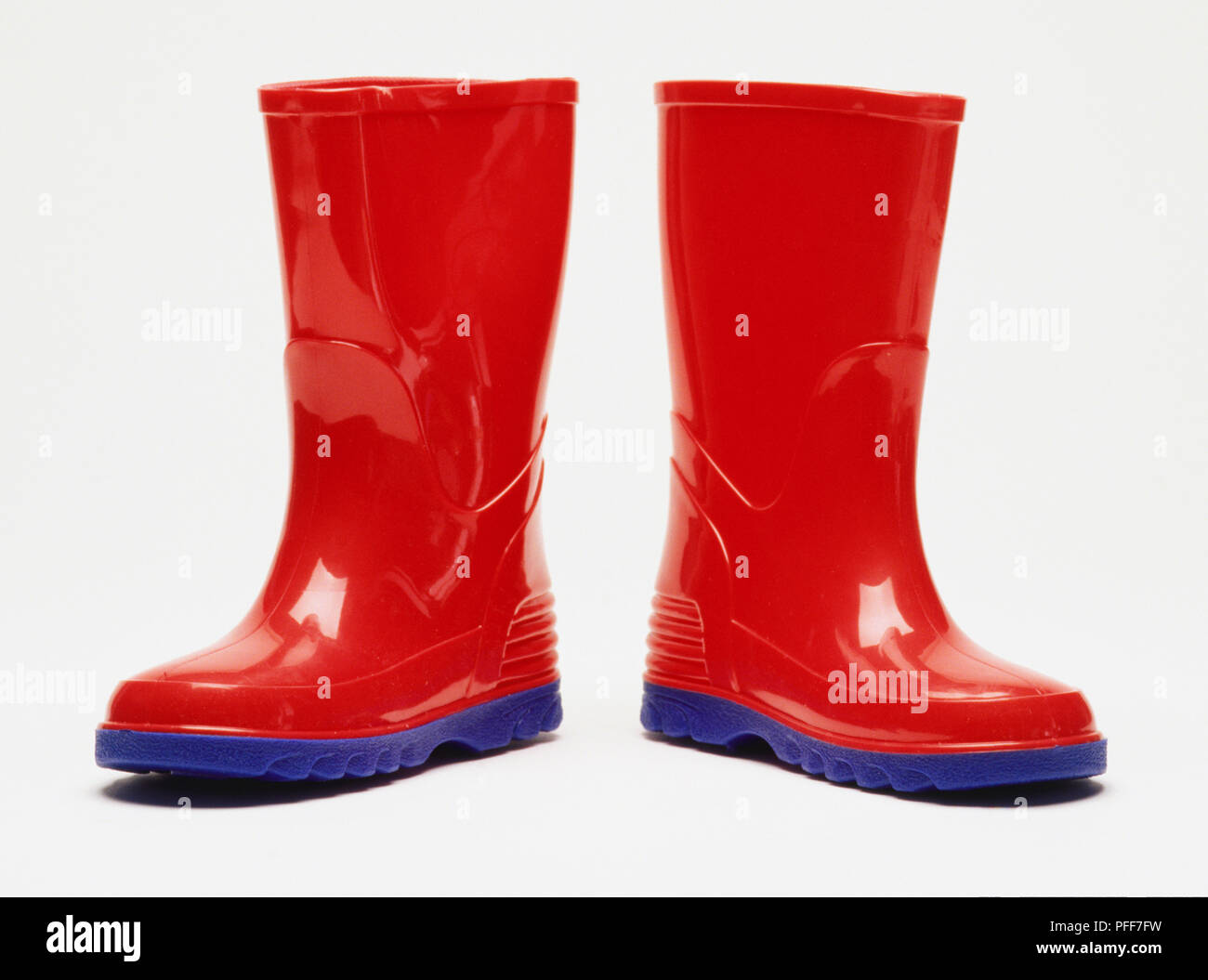 Pair of red rubber rain boots with blue soles Stock Photo - Alamy