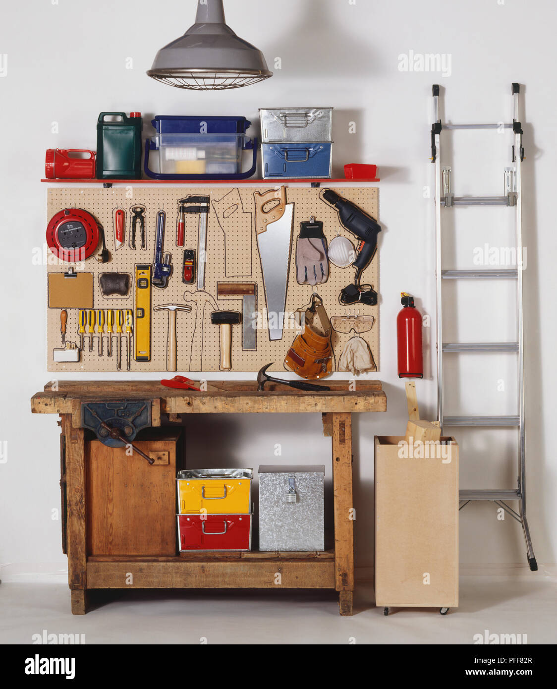 Workbench, metal boxes, work tools hanging on wooden board on wall ...