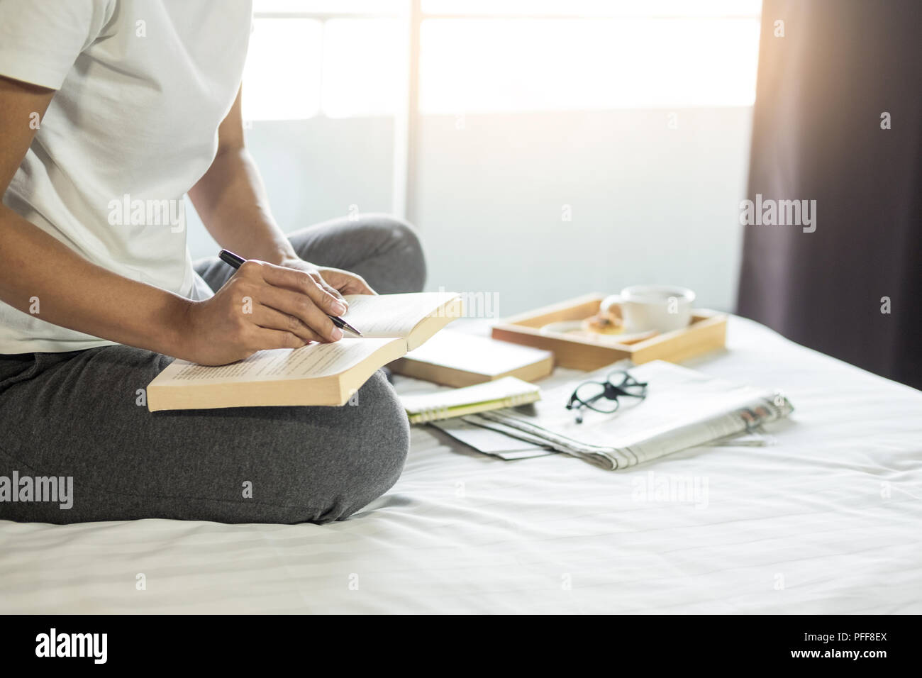 Young woman sitting working and writing in the notebook on bed leisure ...