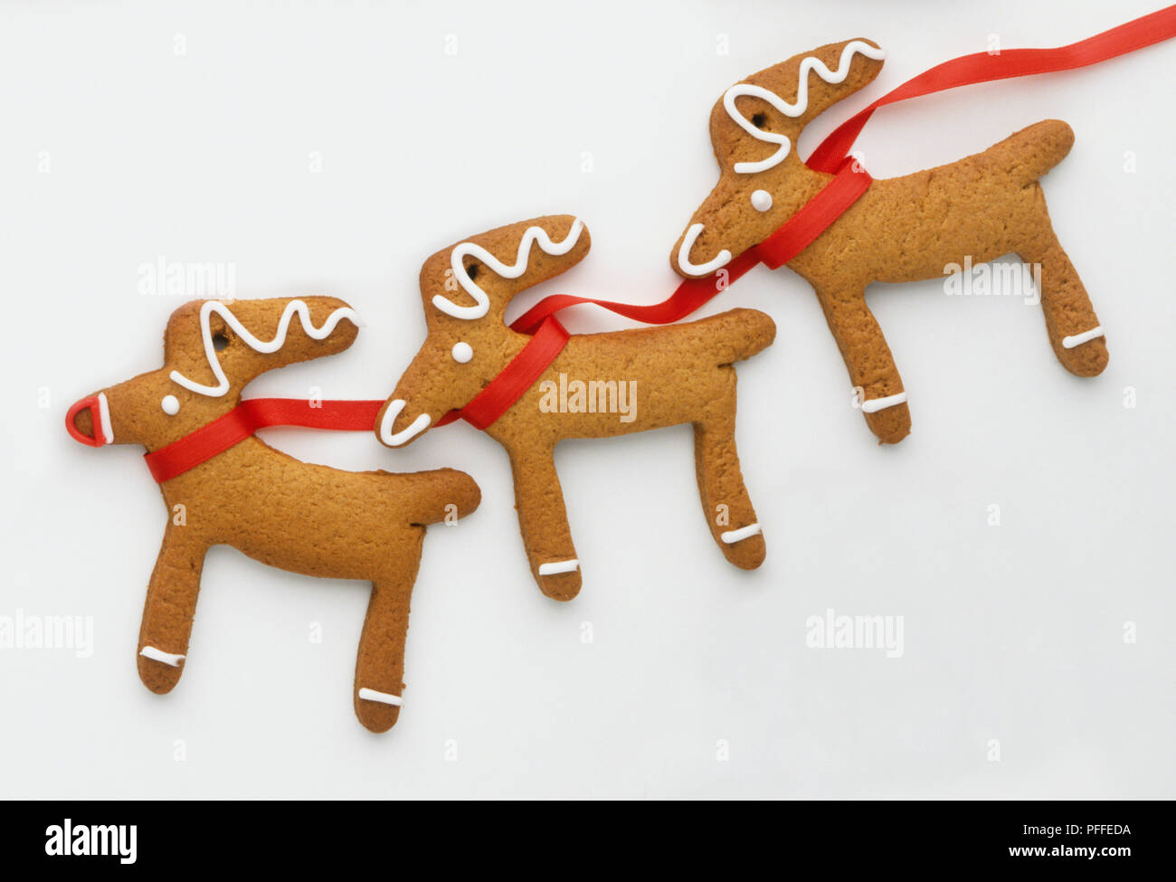 Three reindeer-shaped biscuits with white icing linked together with a ...