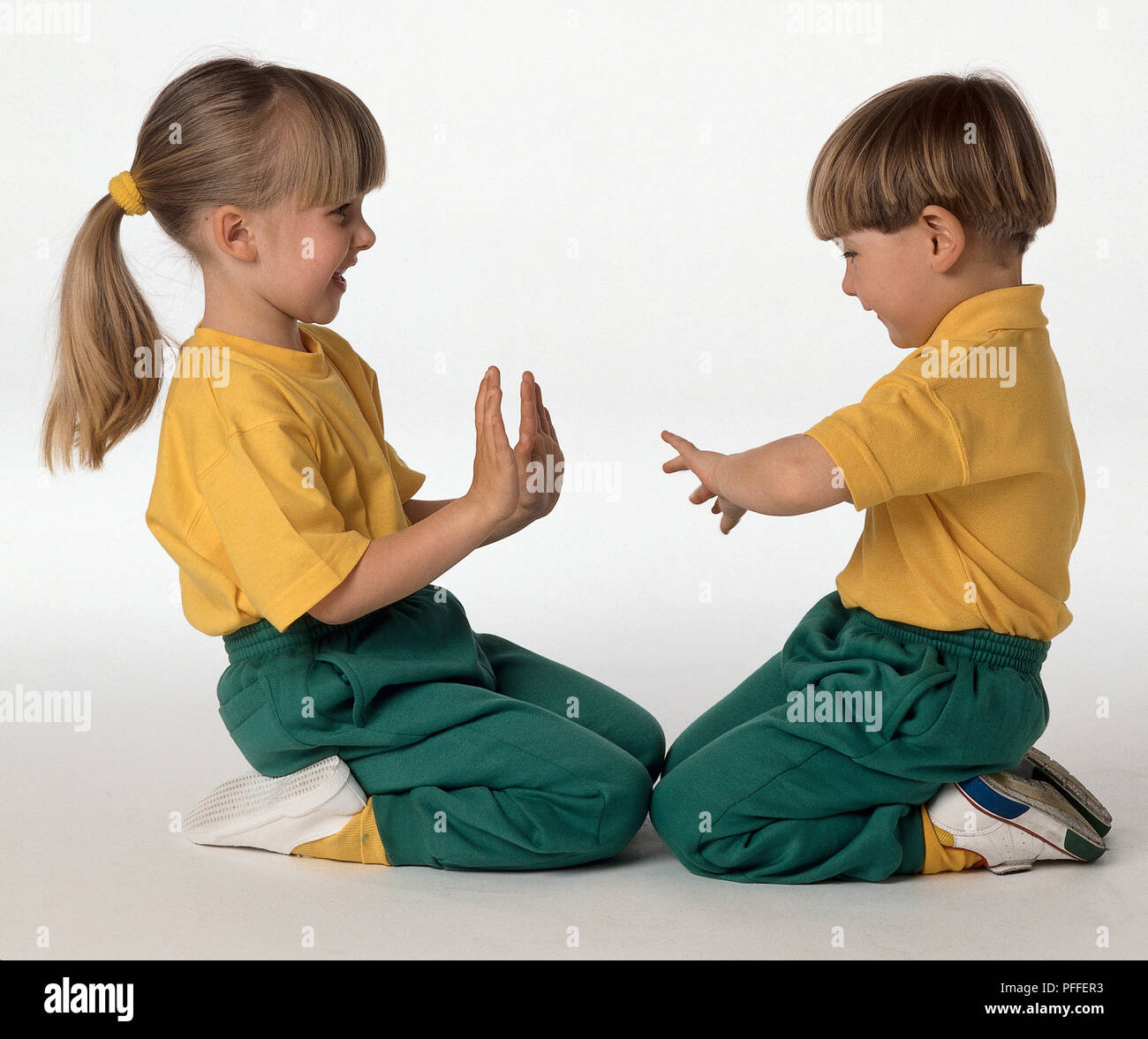 Side view of young Boy and Girl kneeling clapping hands Stock Photo - Alamy