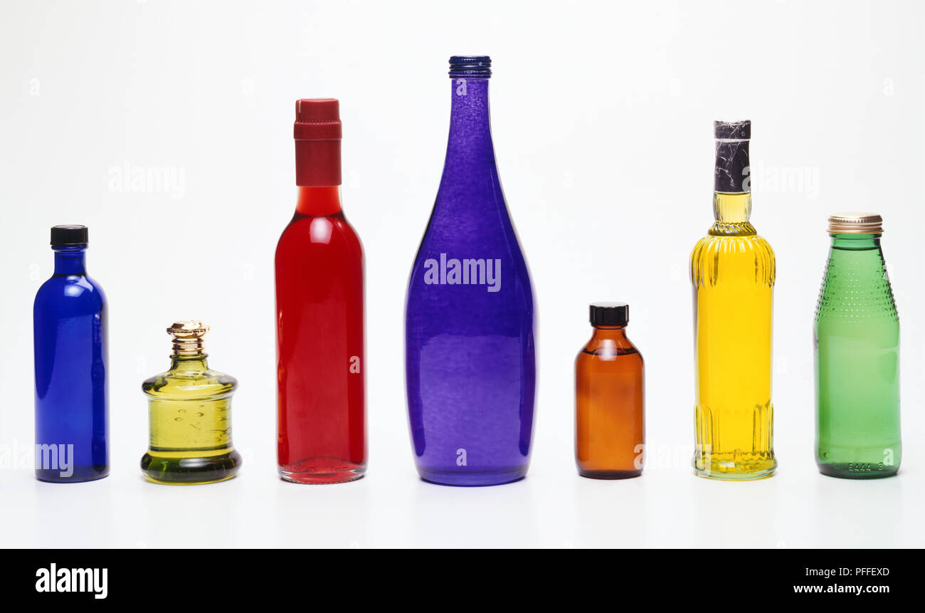 Colourful selection of differently shaped glass bottles, side view ...