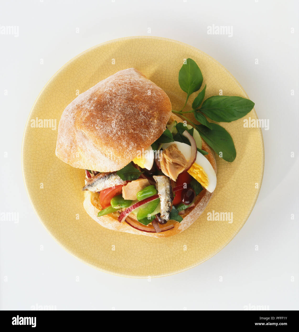 Pan Bagnat, top of bread roll lifted to reveal filling of boiled egg ...
