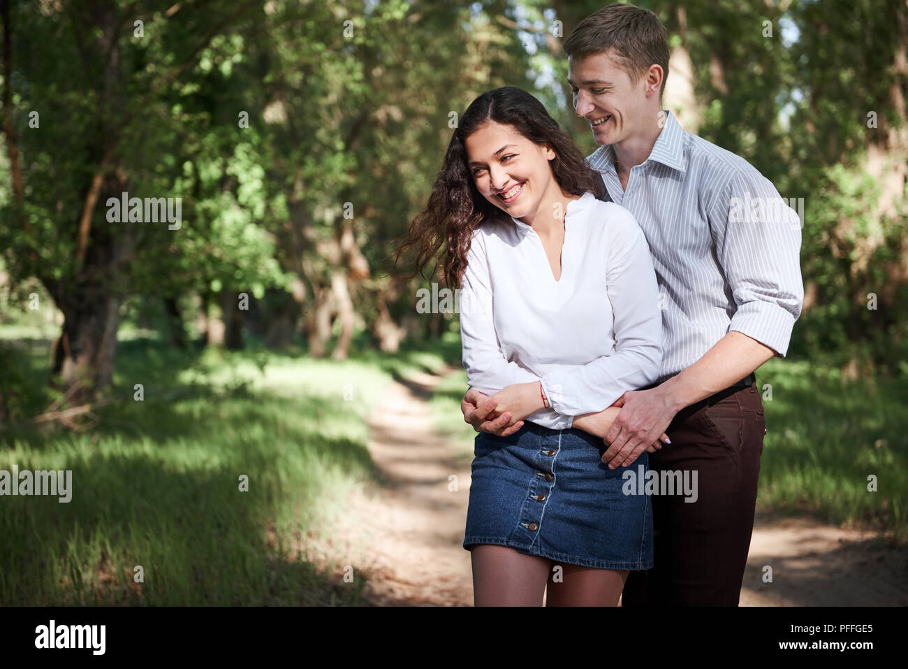 young couple walking in the forest, summer nature, bright sunlight ...