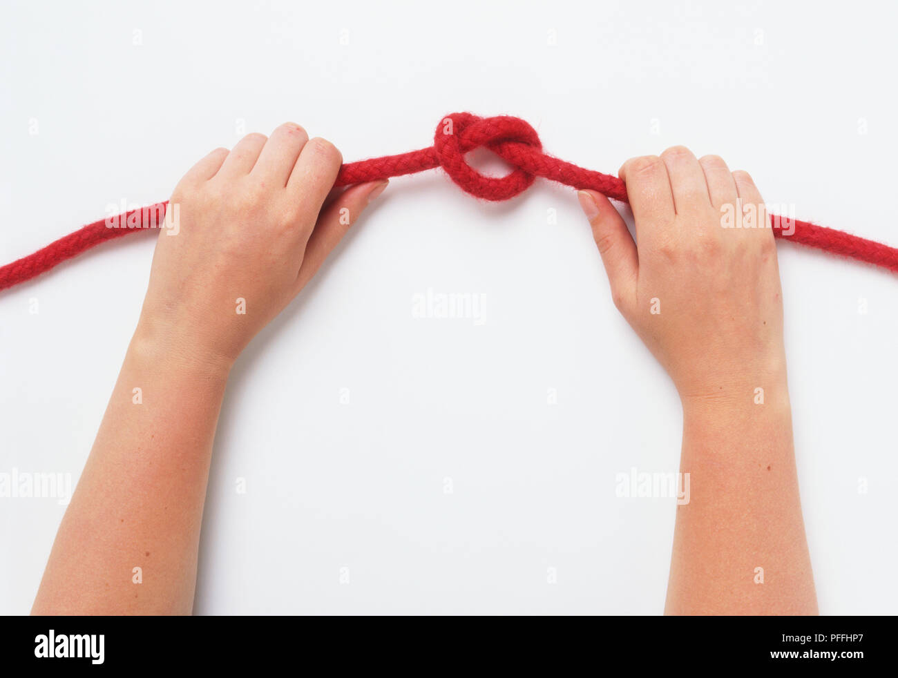 Hands pulling at both ends of a rope to secure a half-hitch knot Stock ...