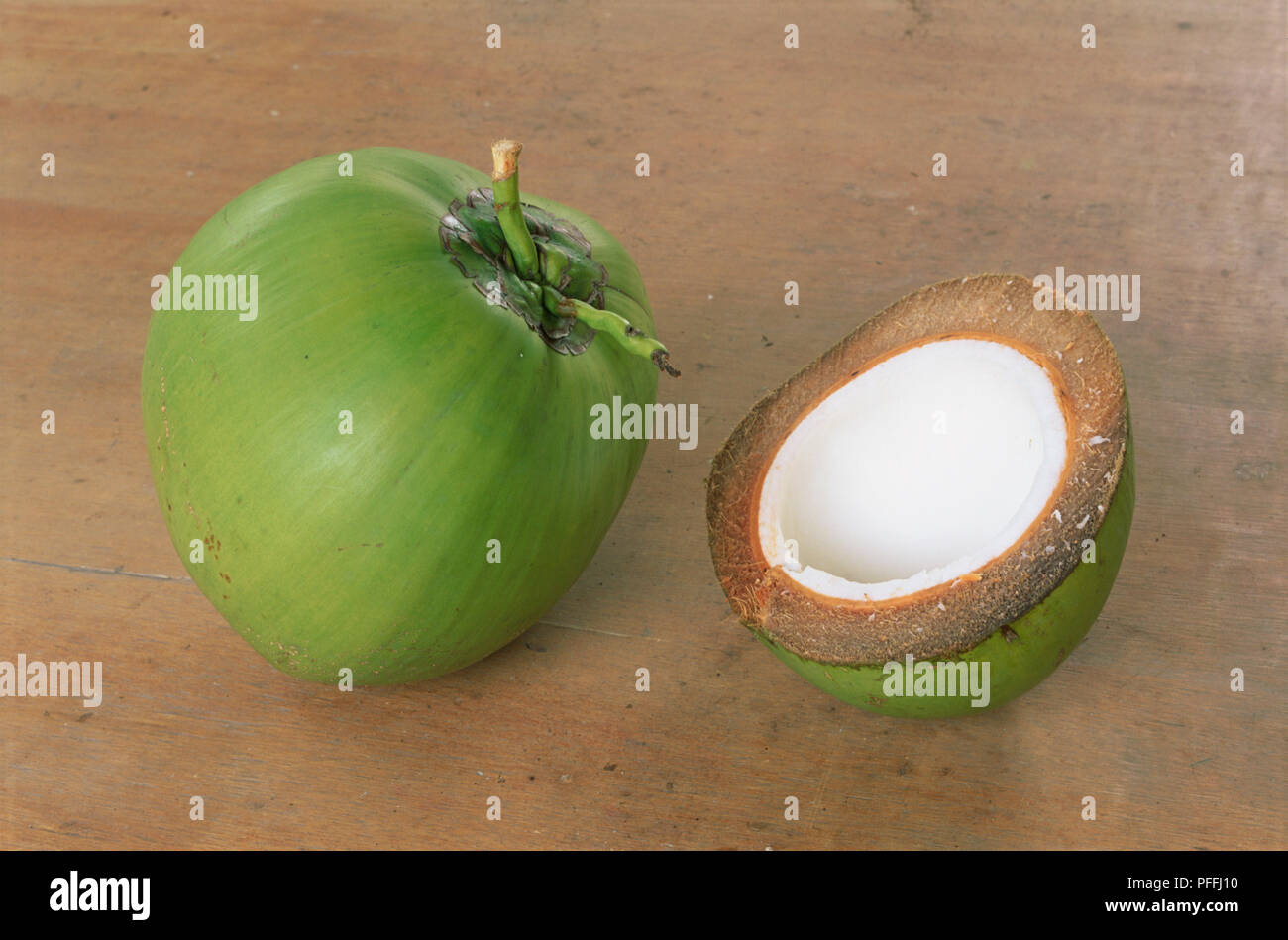 Whole and halved coconut, still in its green casing Stock Photo - Alamy