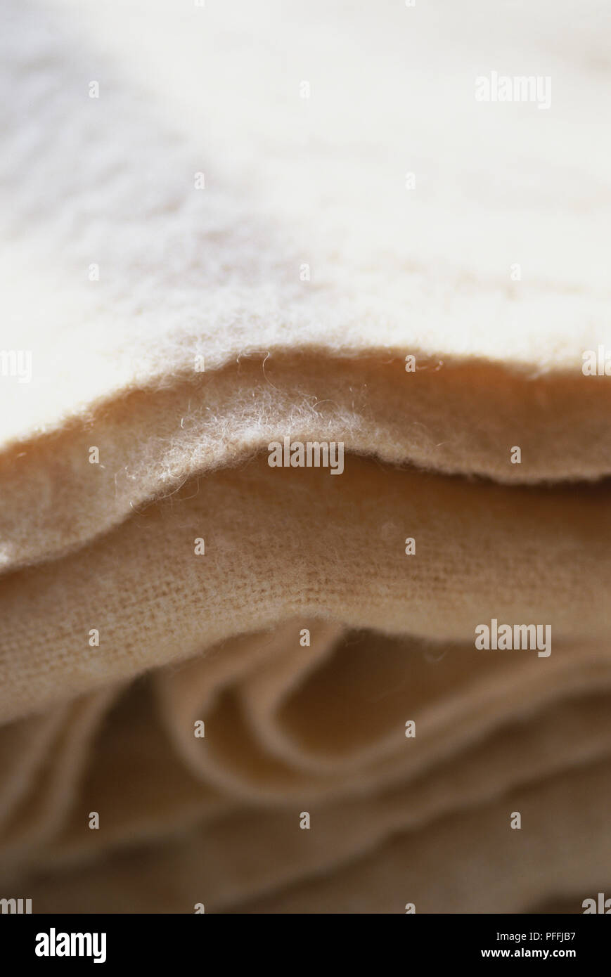 Edges of rolled-up cream woolly blanket, close up Stock Photo - Alamy