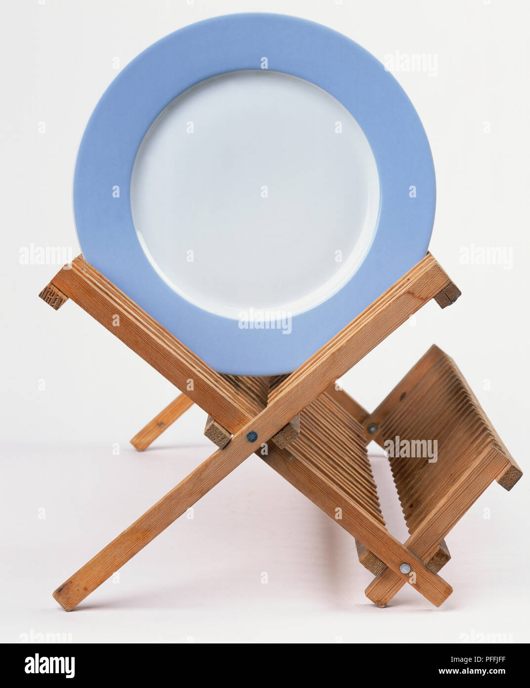 Folding wooden plate rack, round blue plate drying on it, side view ...